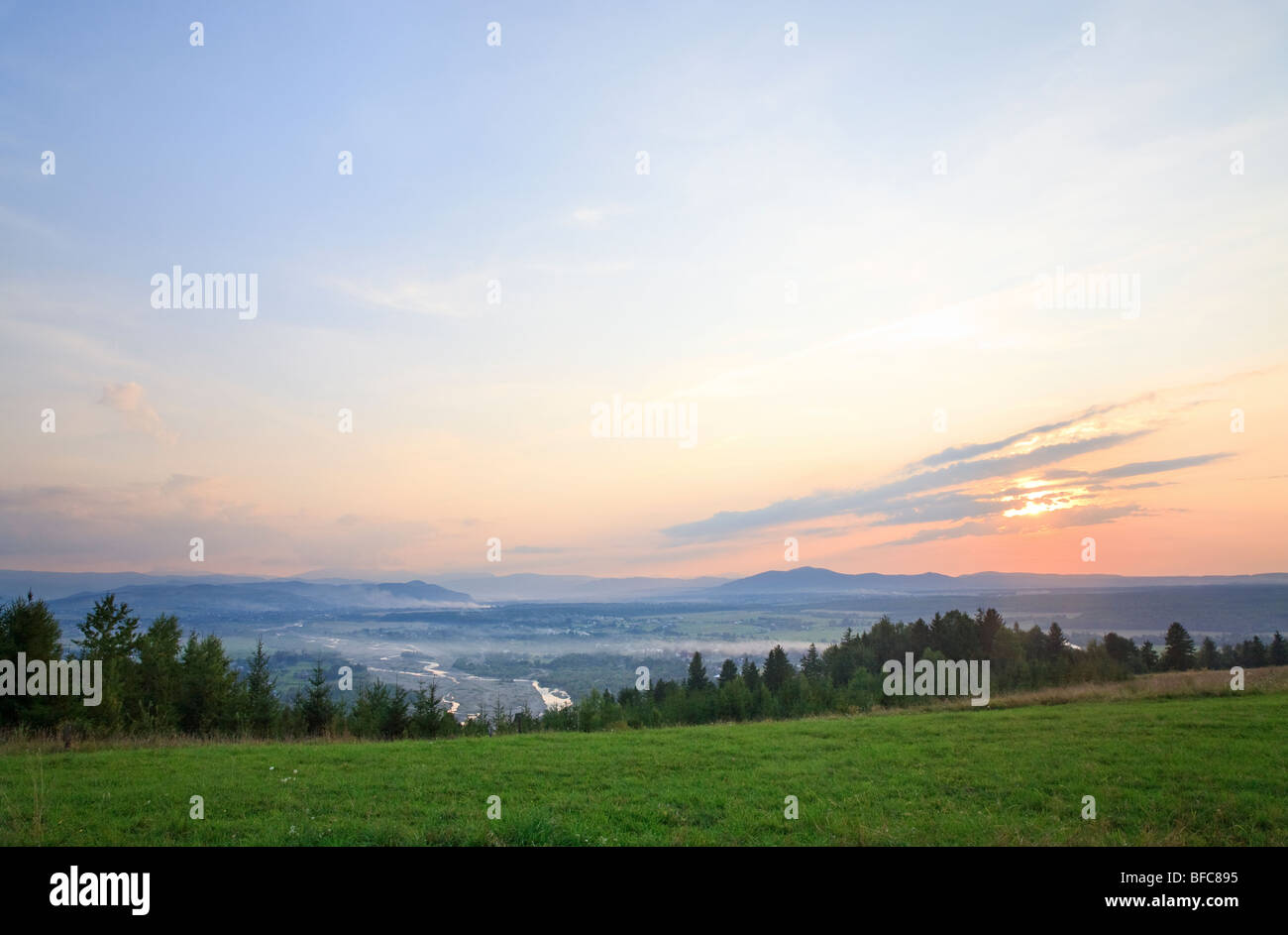summer countryside landscape with river, sunset and mountain behind ...