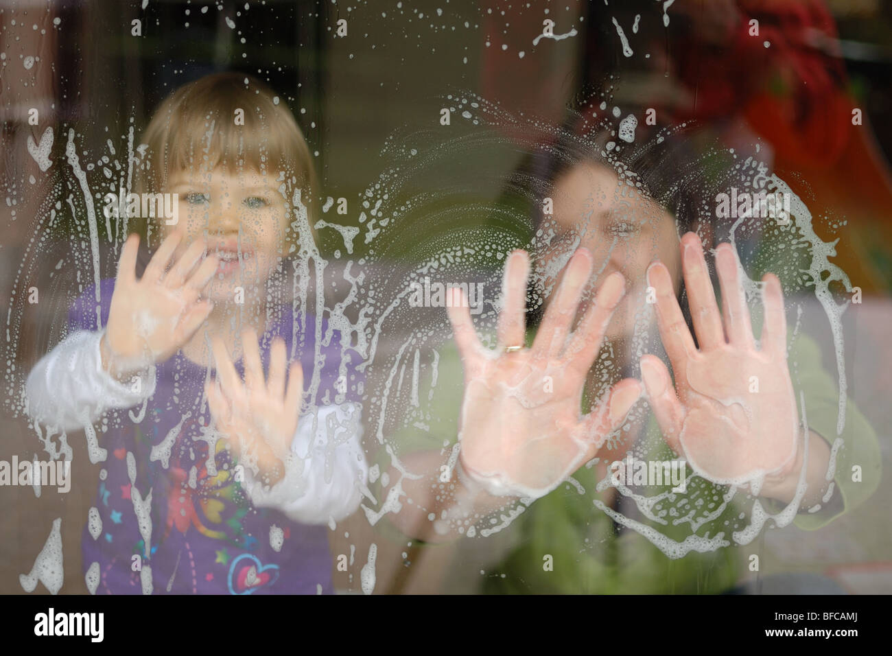 Mother and a child cleaning a window and having fun Stock Photo - Alamy