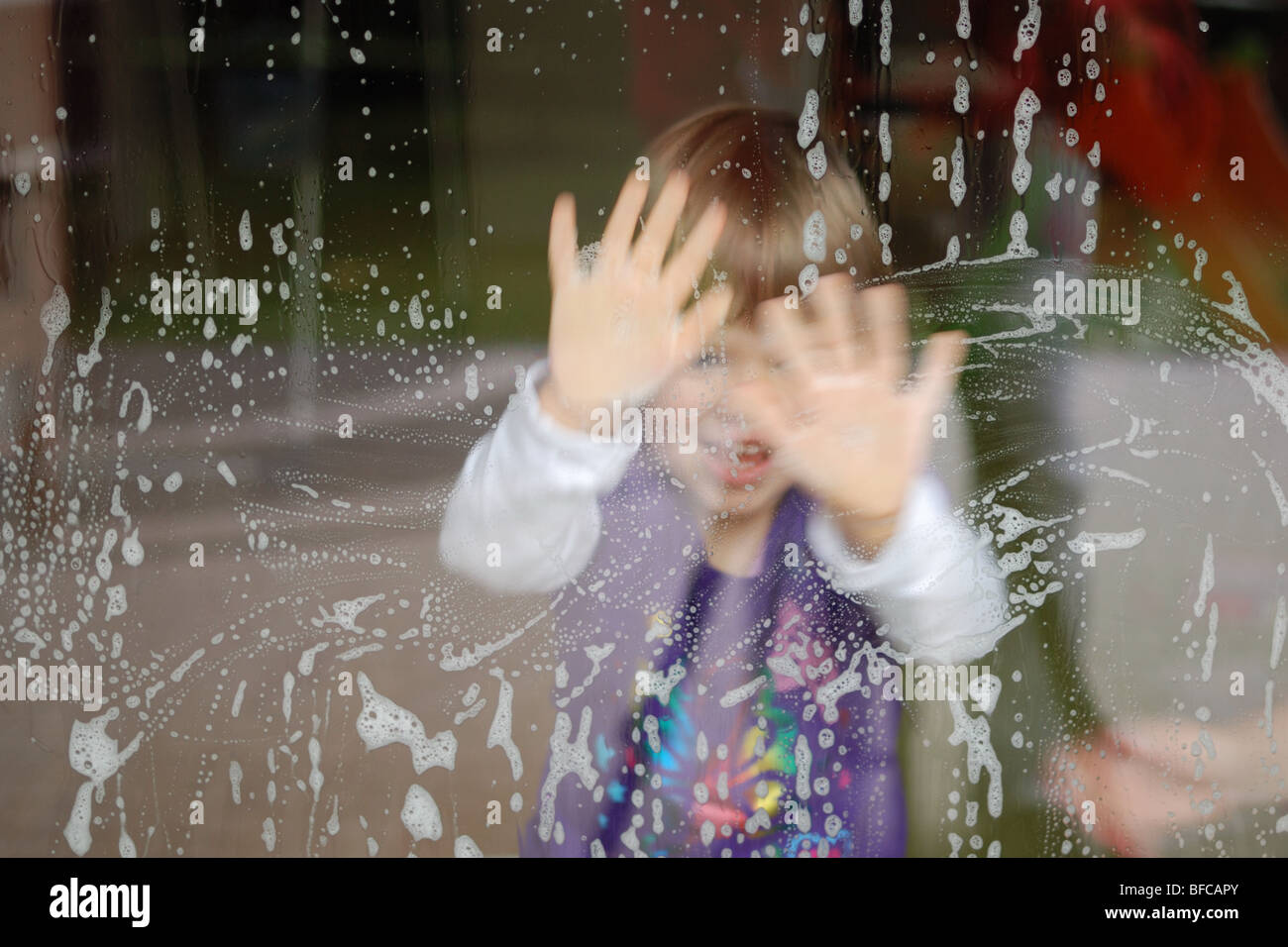 Child cleaning a window and having fun Stock Photo - Alamy
