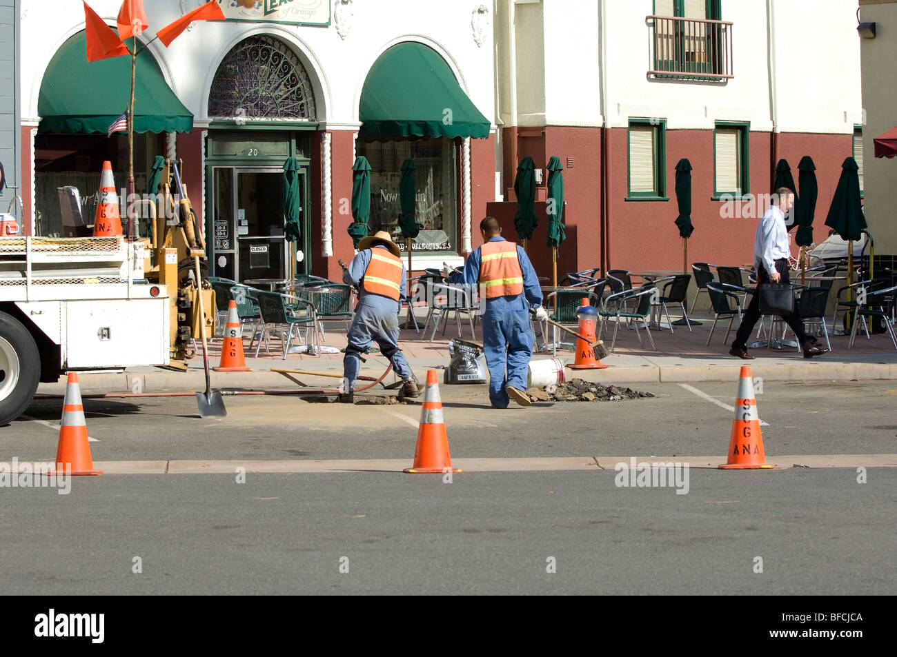 Two hard-working dirty men work on the road while a well-dressed clean ...
