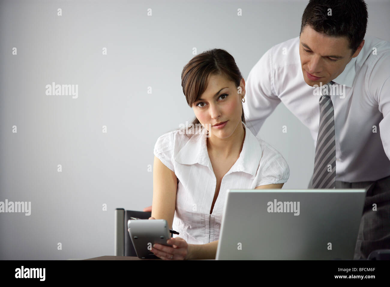 employee at her desk with colleague Stock Photo - Alamy