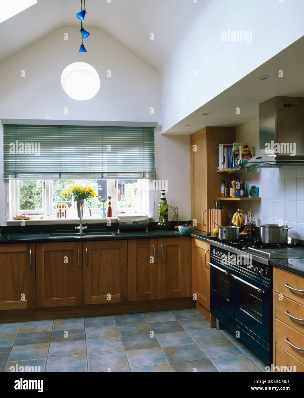 Green slatted blind in modern kitchen extension with range oven and ...