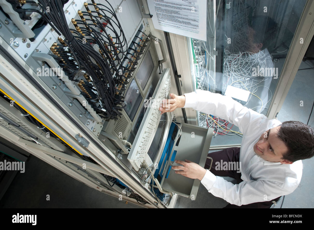 male engineer working on keyboard in computer server cabinet viewed ...