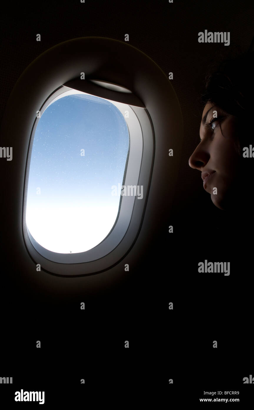 Beautiful woman looking outside airplane's window Stock Photo - Alamy