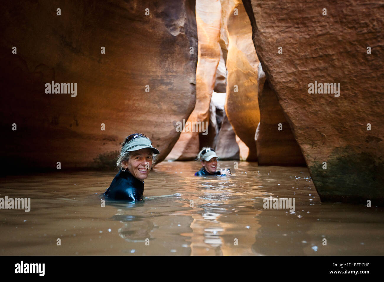 Two women wading through a deep pool in a slot canyon in Utah Stock ...
