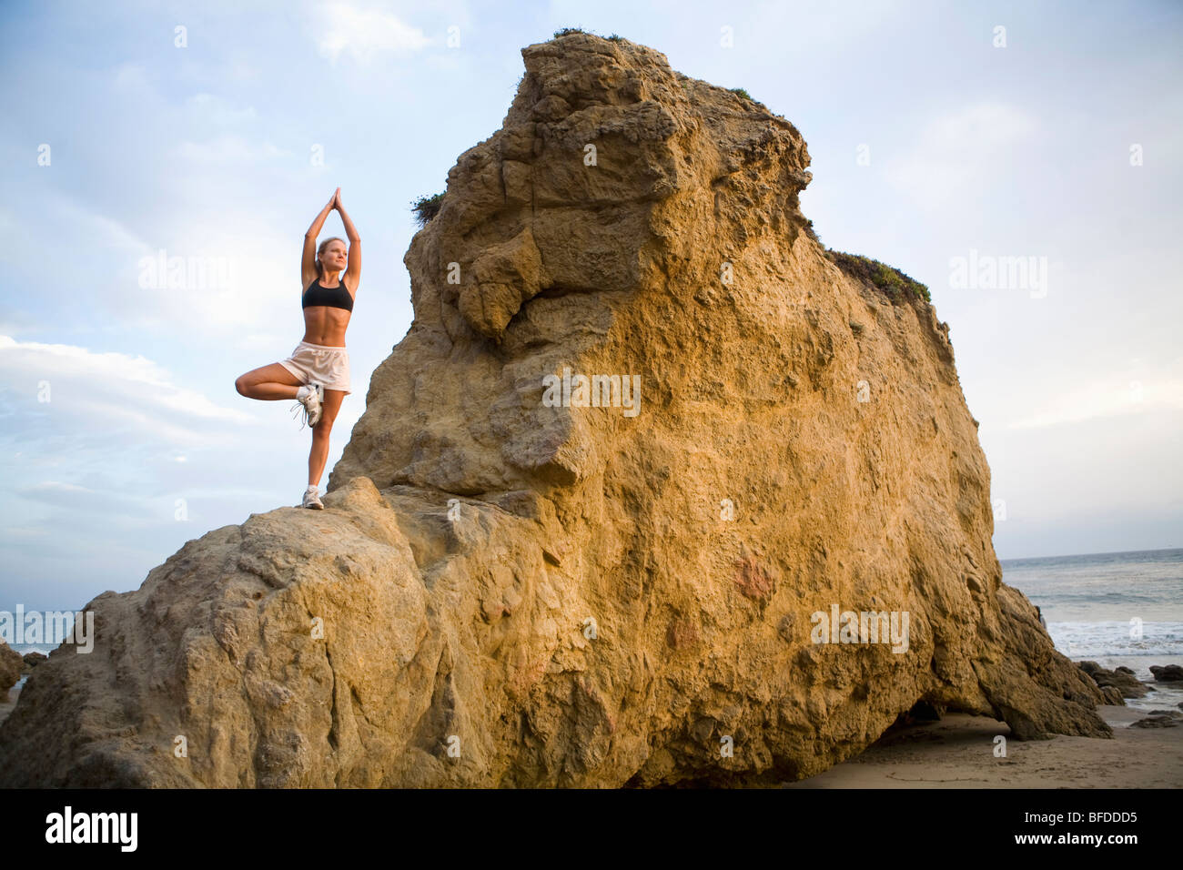 A young woman preforming the yoga posture Tree Pose on the beach Stock ...