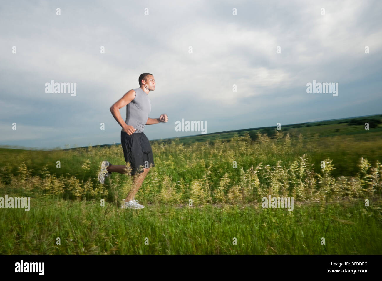 Young man running on grass trail through a bright green field at Spirit ...