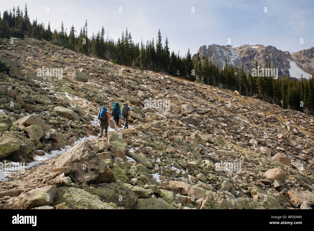A man and two women hiking through a talus field on the Fern Lake Trail ...