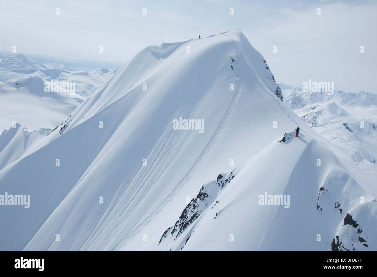 Two skiers on a snowy mountain getting ready to drop in Haines, Alaska ...