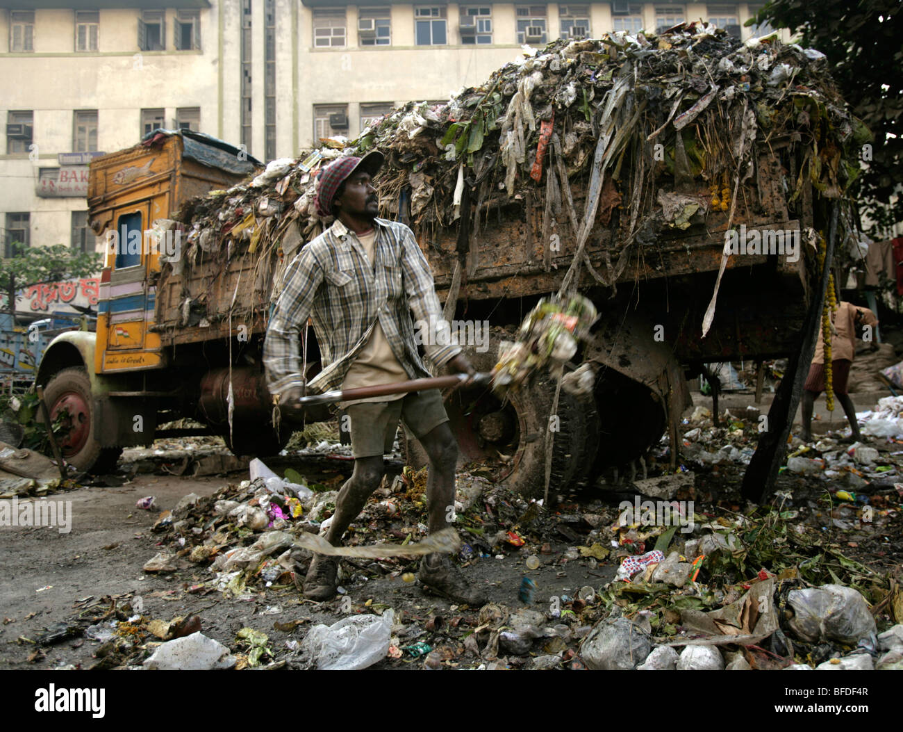 A garbage man shovels garbage into an impossibly over loaded garbage ...