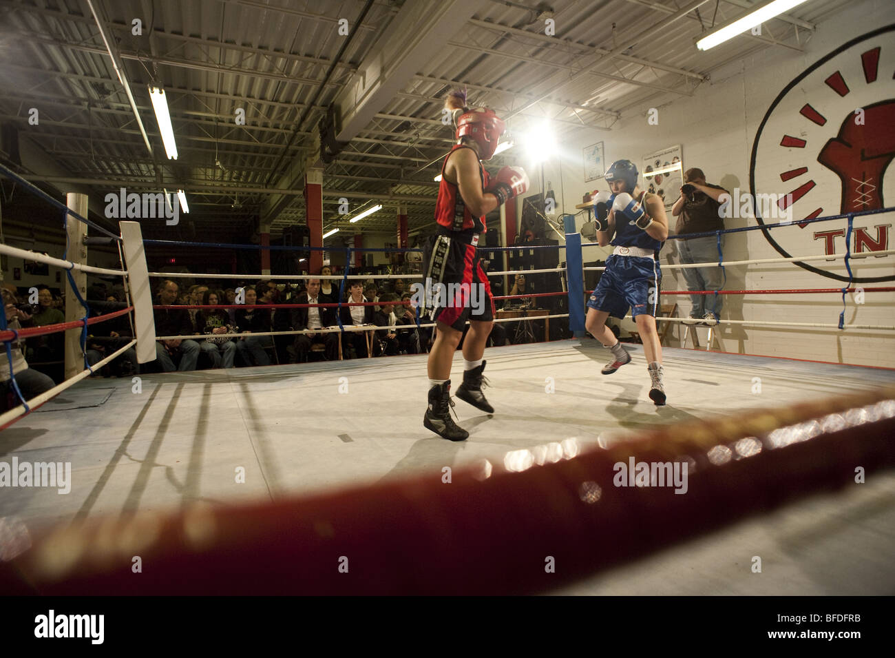 Two female boxers compete during a fight while judges and fans watch ...