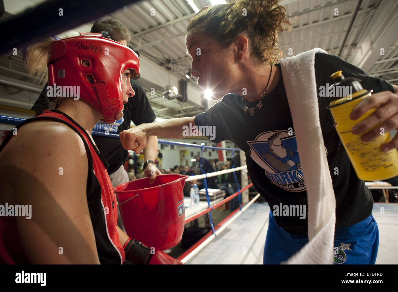 Female coach demonstrates a punch to a female boxer during a break ...