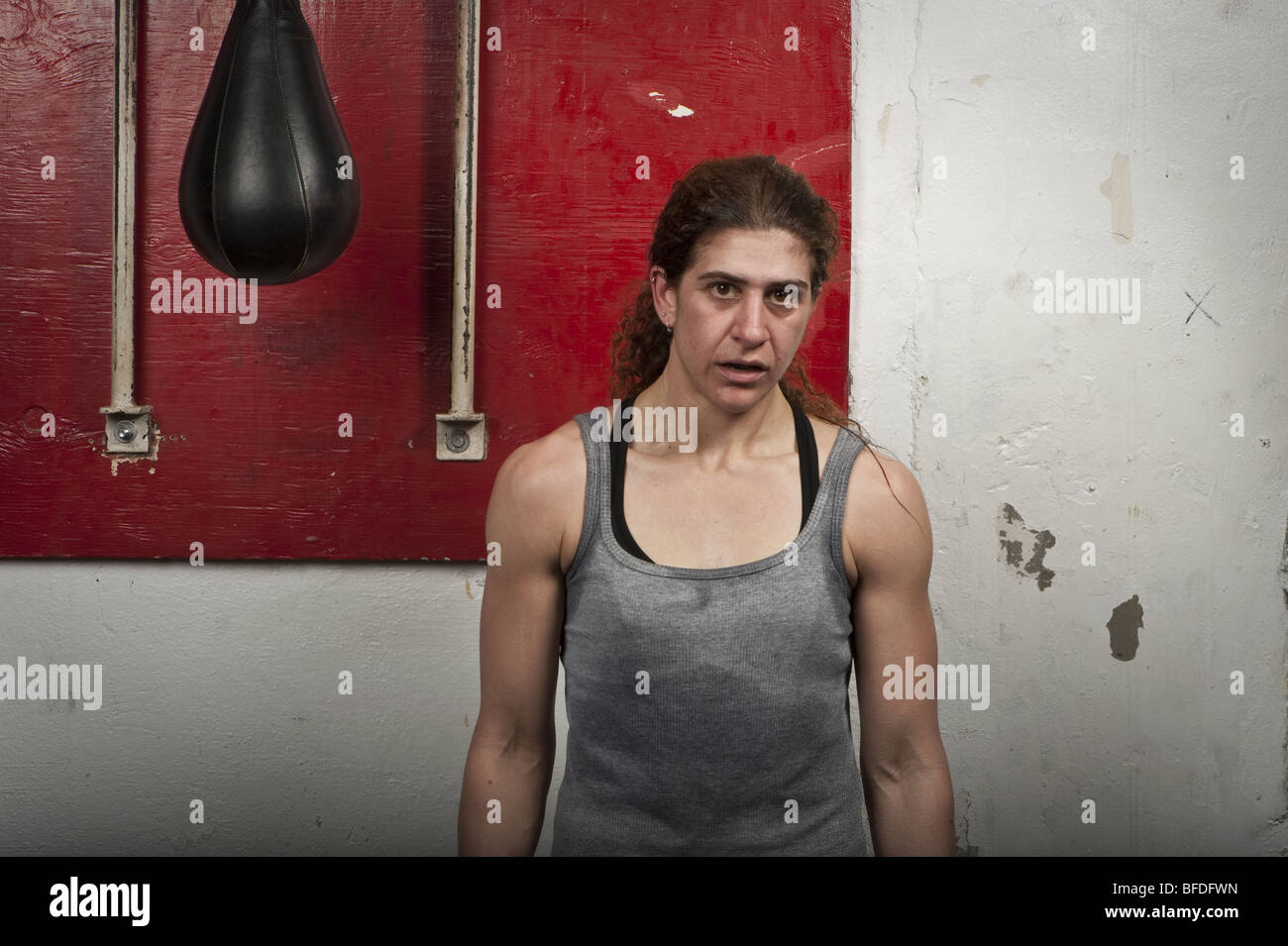 Portrait of exhausted female boxer in gym with boxing bag immediately ...