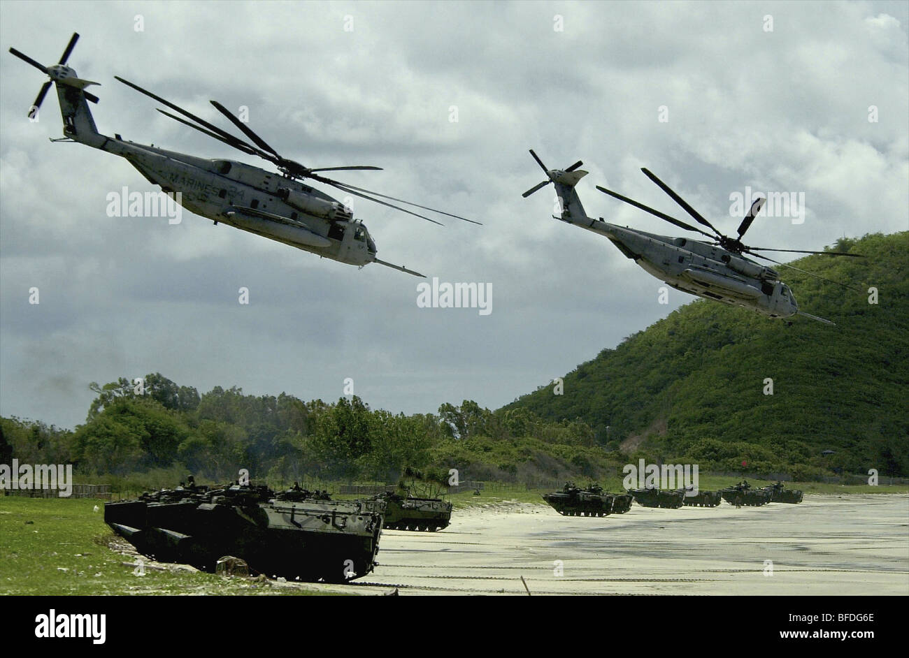 Helicopters fly over while amphibious vehicles land on a Thai beach ...