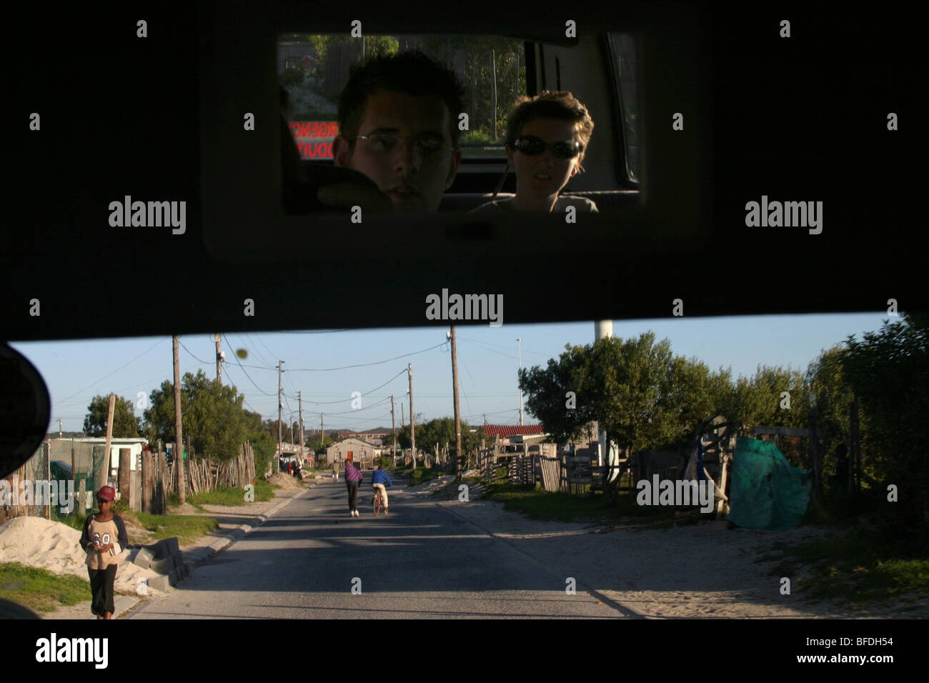 Tourists, as seen in the rearview mirror, view the townships while on a ...