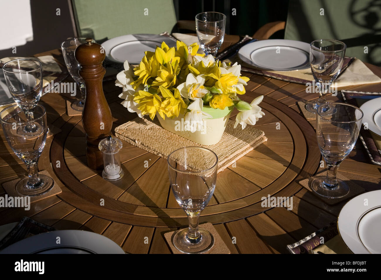 Dinner setting with flower display on an outside round wooden table ...