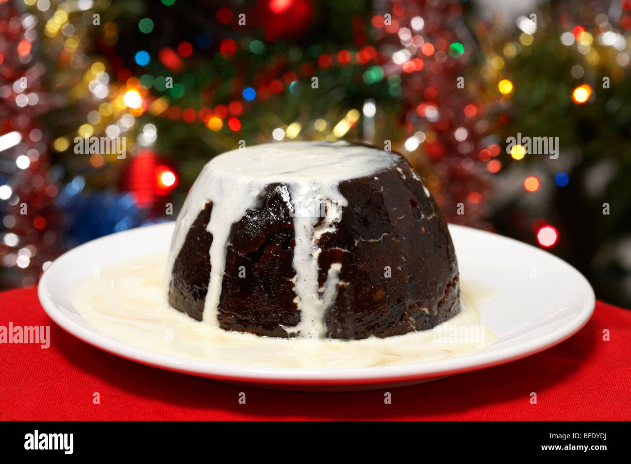 traditional christmas pudding covered in fresh cream on a plate in ...