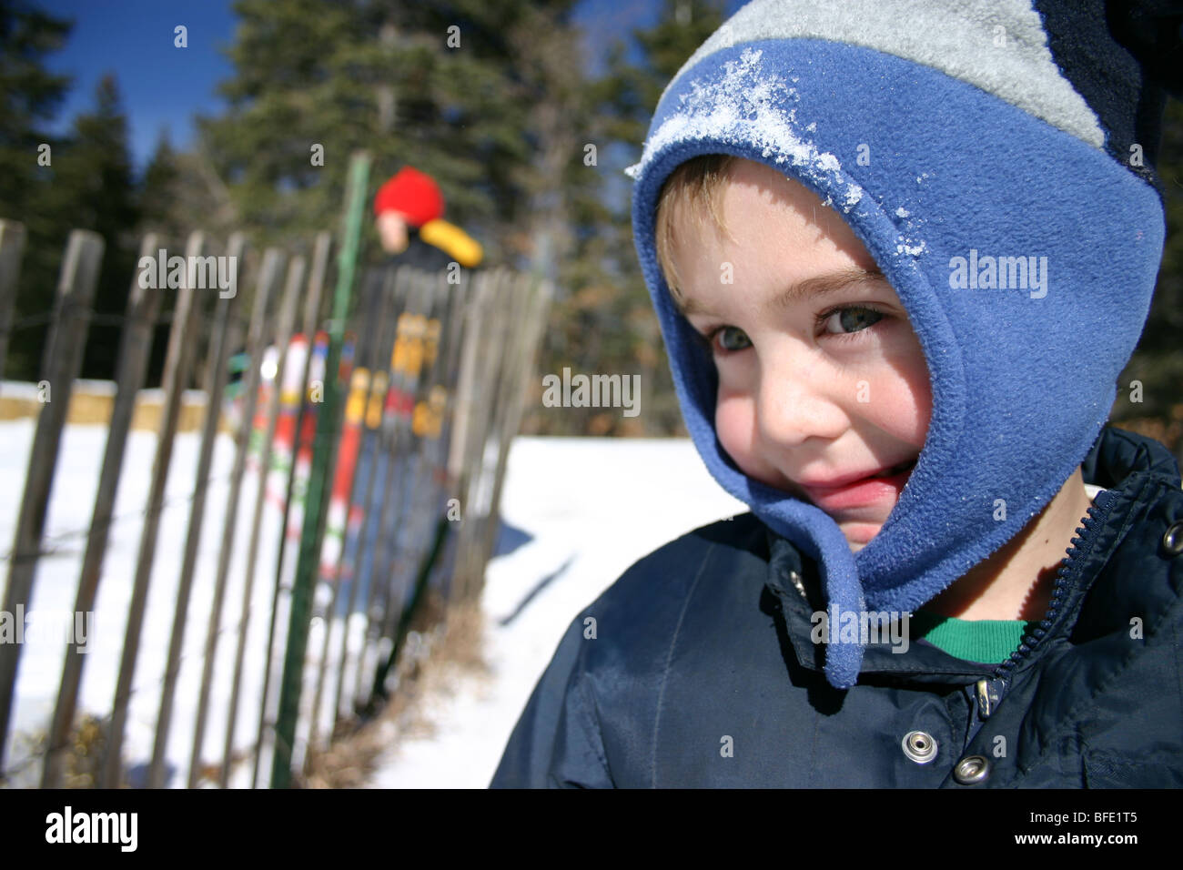 child getting ready to go sledding, wearing a winter hat sprinkled with ...