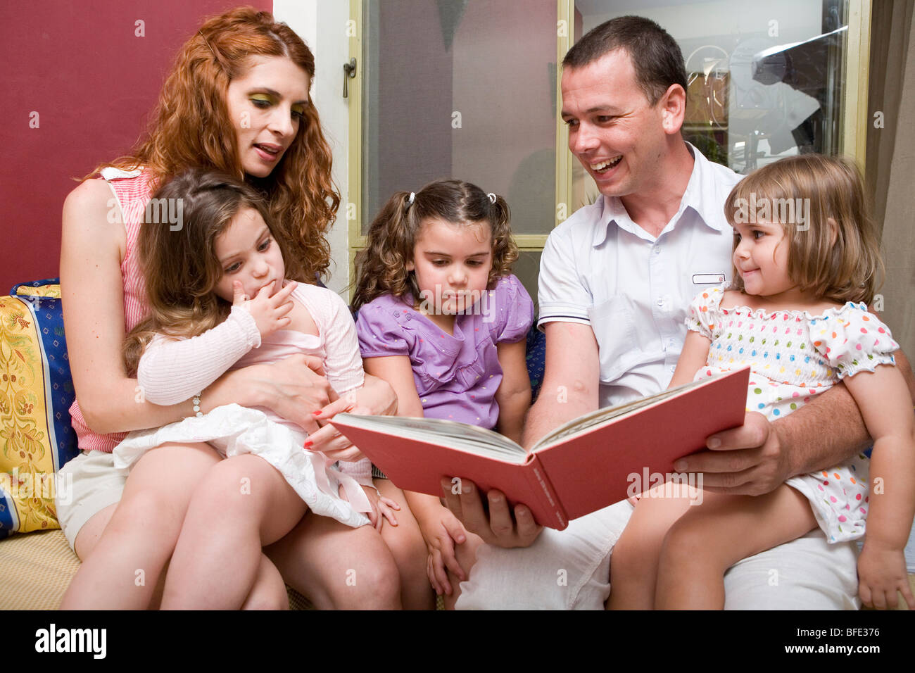 Parents and daughters reading a book together Stock Photo - Alamy