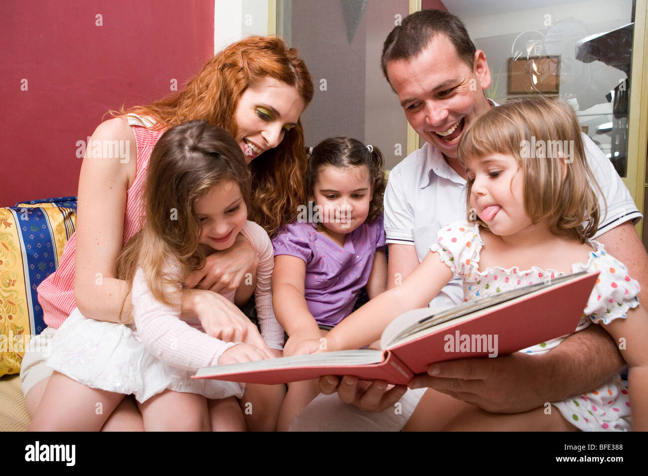 Parents and daughters reading a book together Stock Photo - Alamy