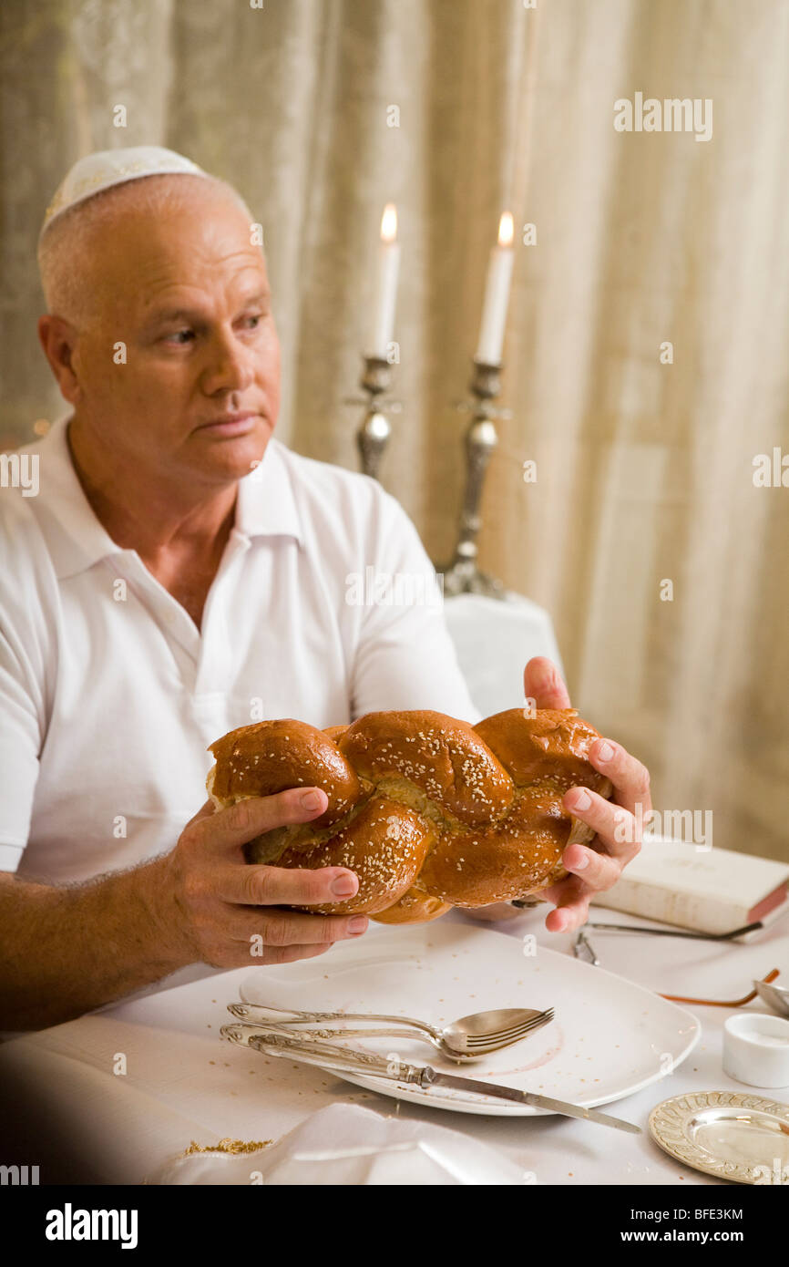 Man blessing on Challah bread at a festive family dinner Stock Photo ...