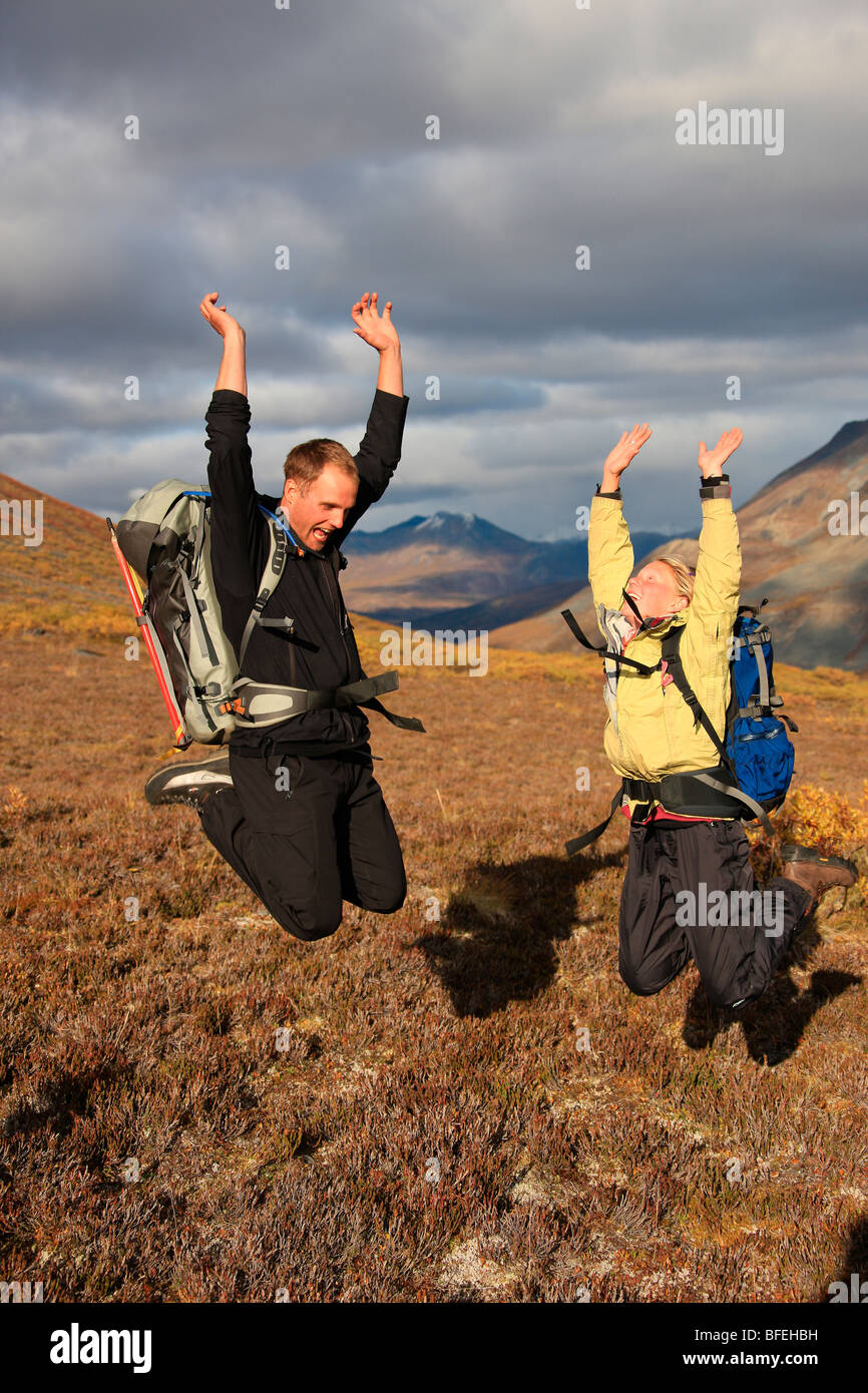 Hikers jumping in the tundra at sunset, Tombstone Territorial Park ...