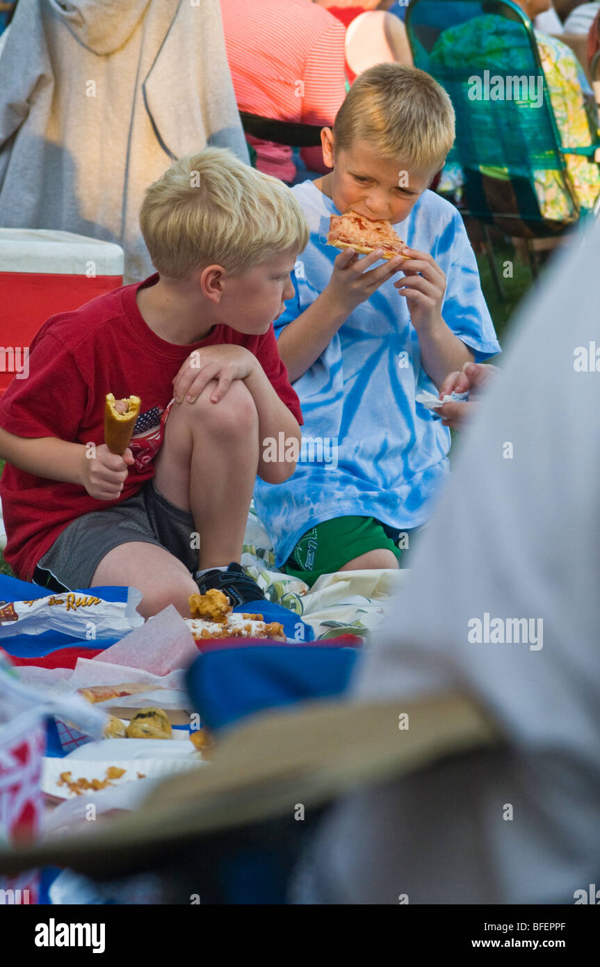 Two young boys eating pizza at family picnic in the park Stock Photo ...