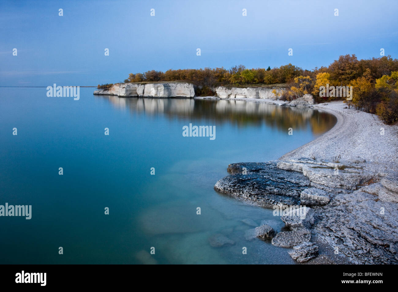 Reflection of cliffs and fall colors on Lake Manitoba at sunset at ...
