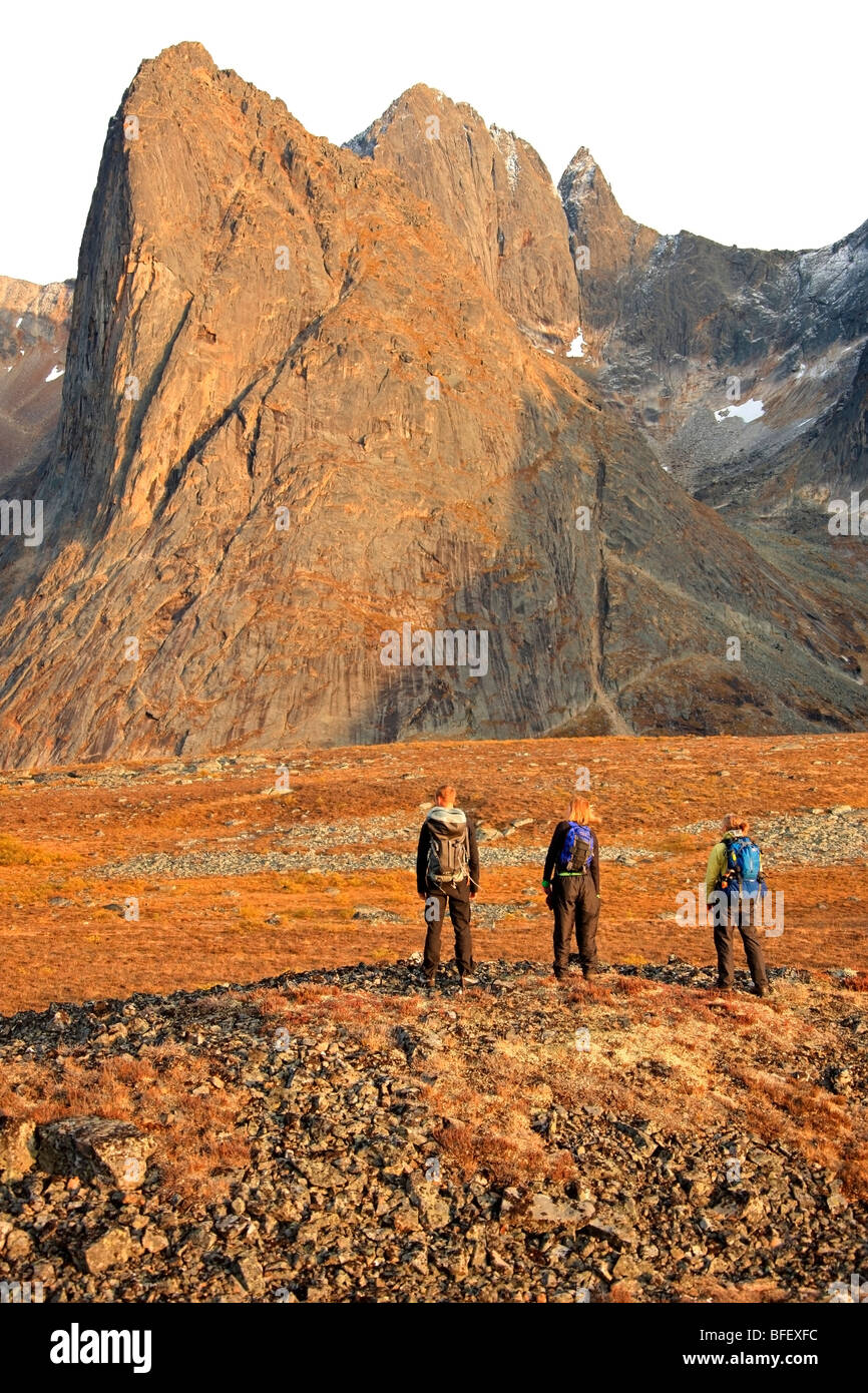 Three hikers standing on a rock pile at sunset looking at Mount ...