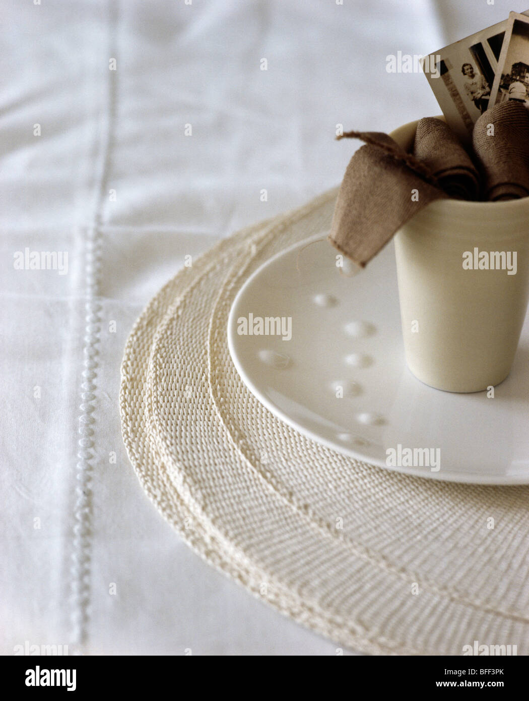 Close-up of cream ceramic cup and saucer on textured cream table-mats ...