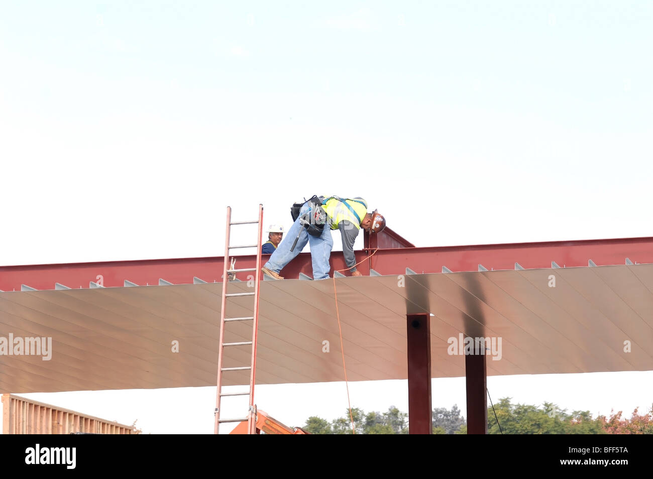 Skilled steel or construction workers climb a ladder and work atop a ...