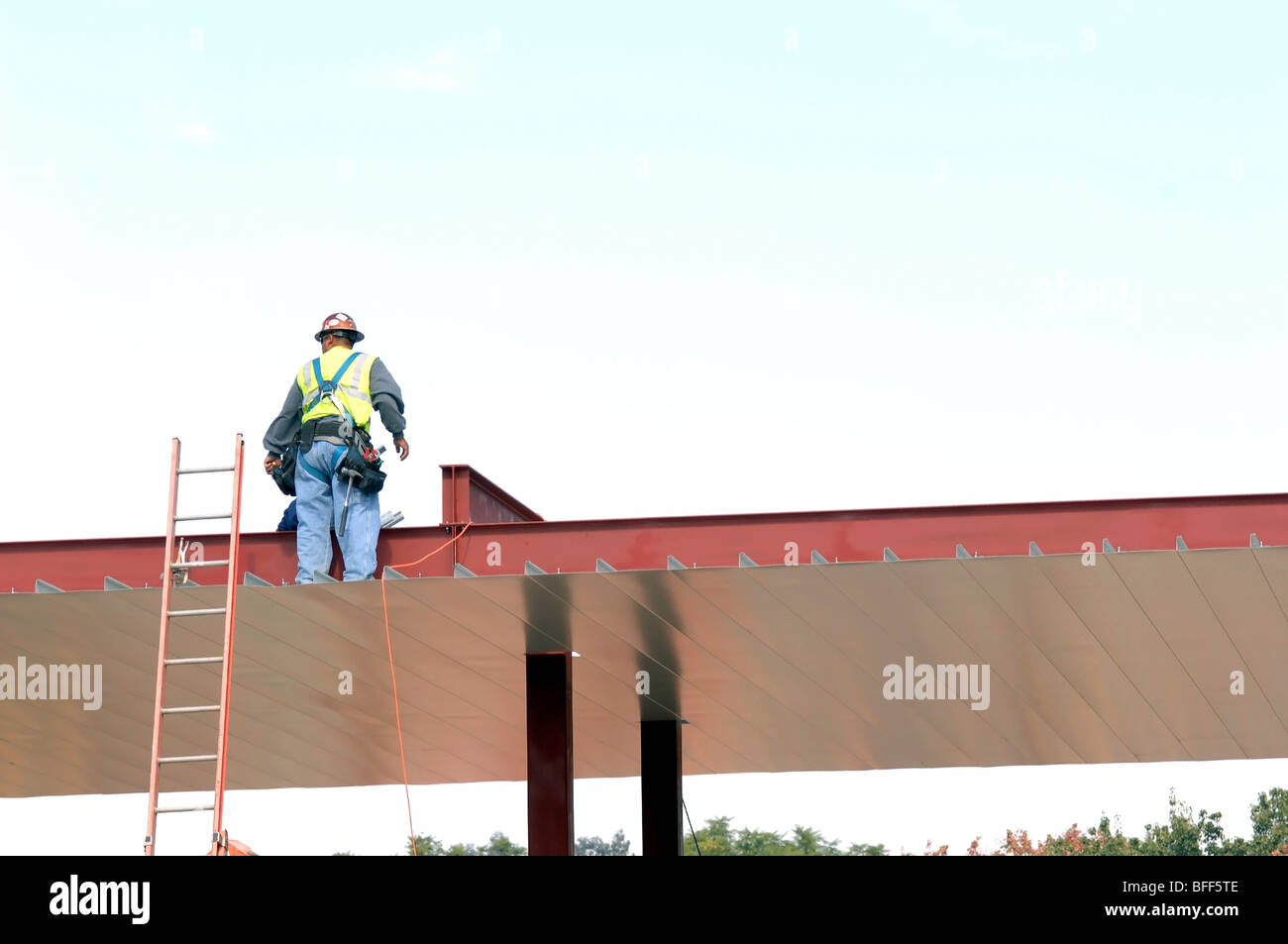 Skilled steel or construction workers climb a ladder and work atop a ...