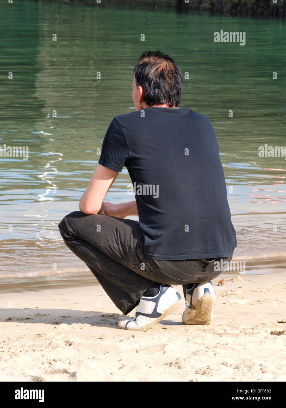 Man looking at the water Stock Photo - Alamy