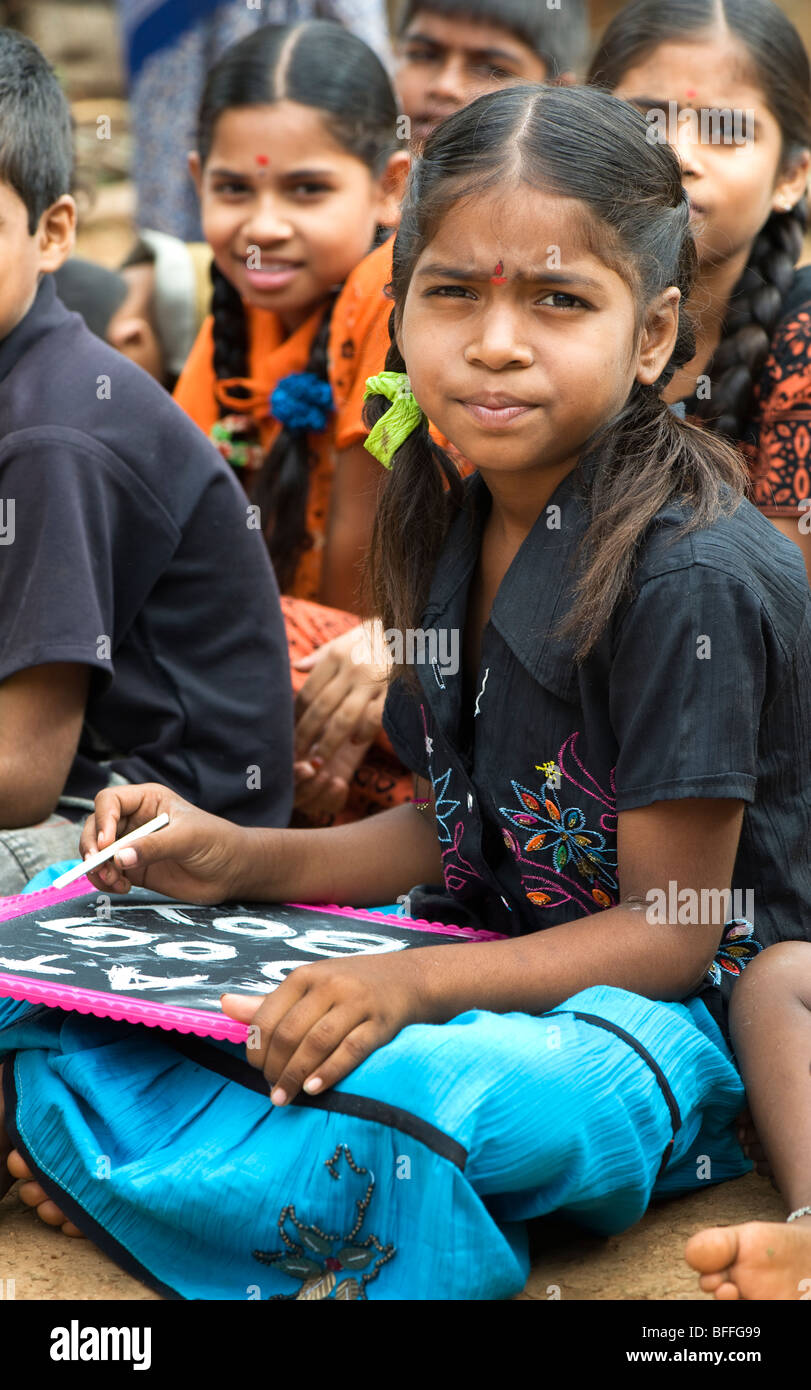 Indian school children sitting outside their school writing on ...