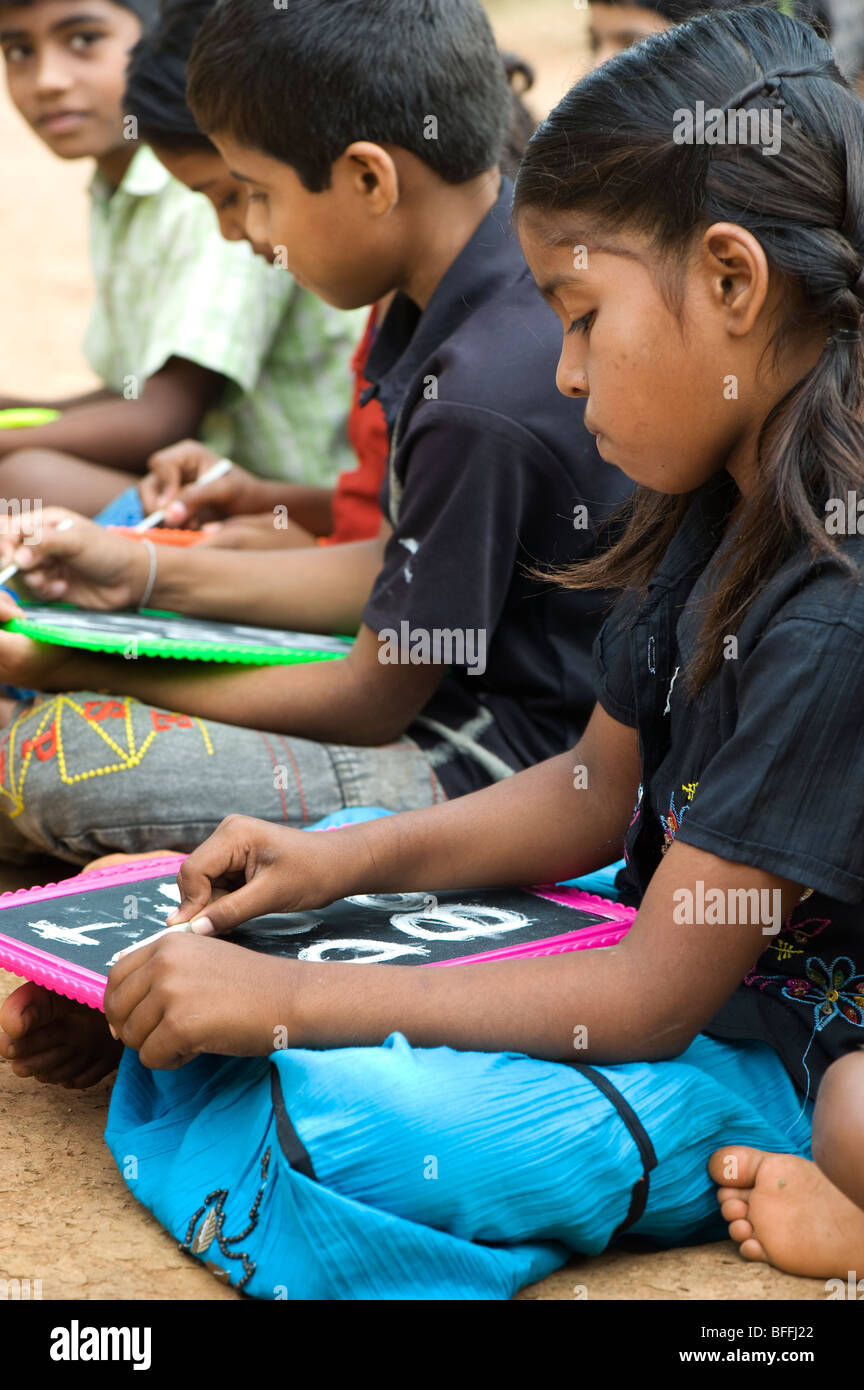 Indian school children sitting outside their school writing on ...