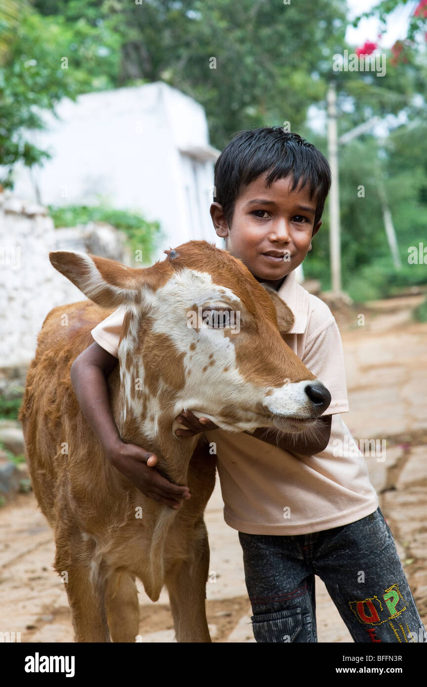 Young indian boy hugging a calf in a rural indian village. Andhra ...