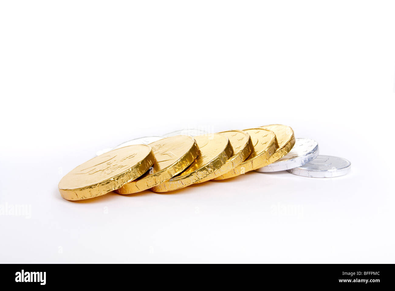 Gold and silver foil wrapped chocolate euro's against white background ...