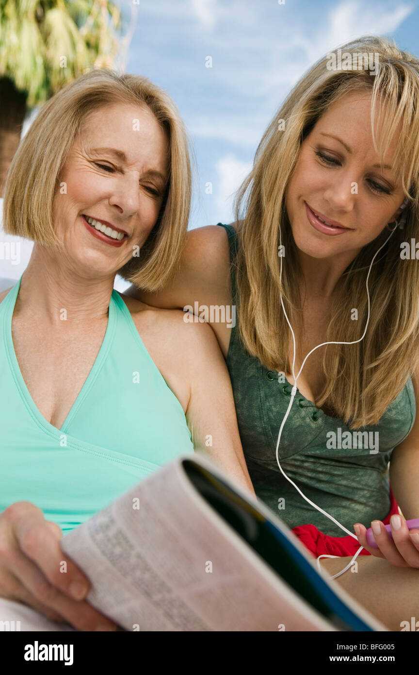 Two women reading magazine outdoors Stock Photo - Alamy
