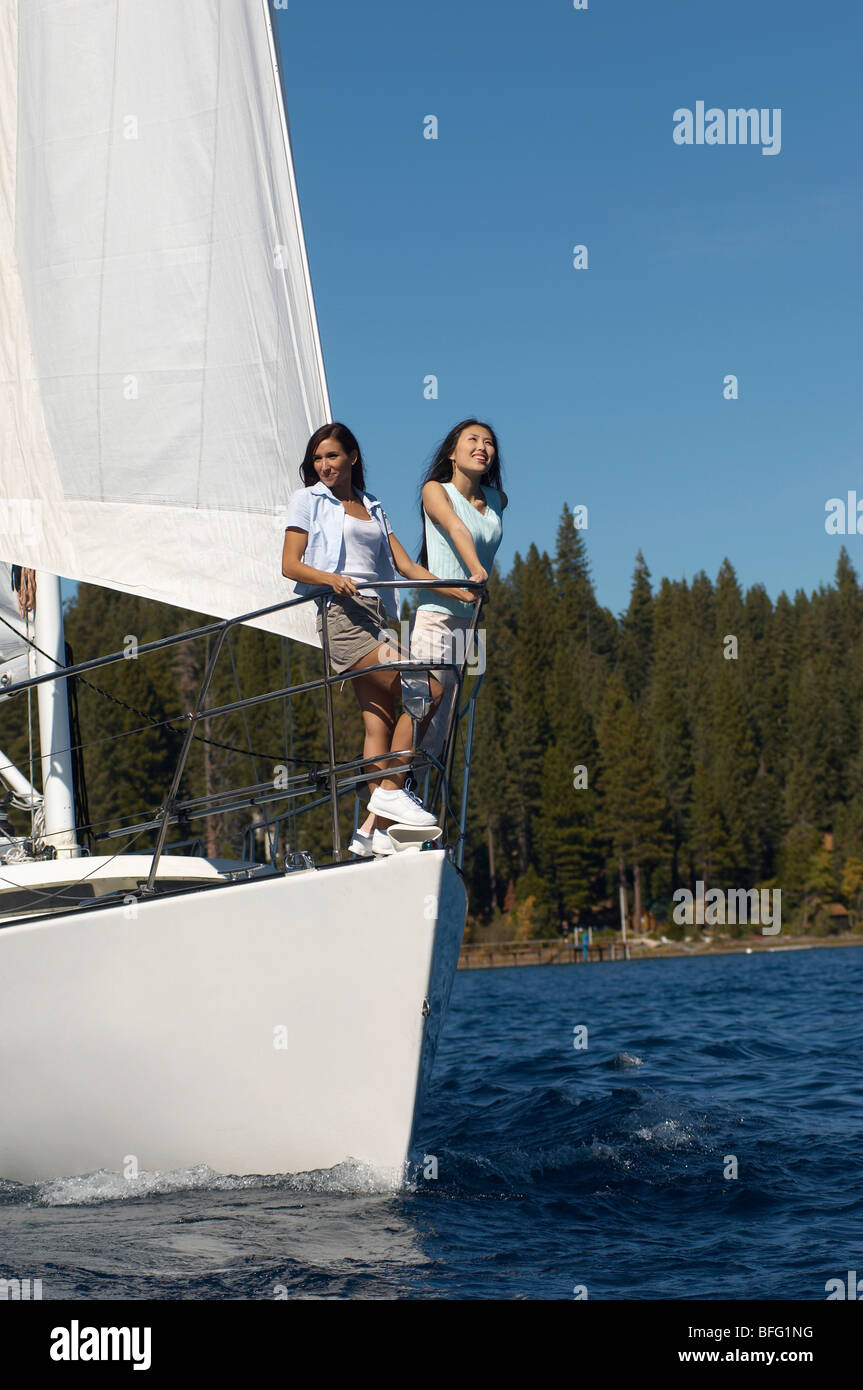 Two young women standing on bow of sailboat Stock Photo - Alamy