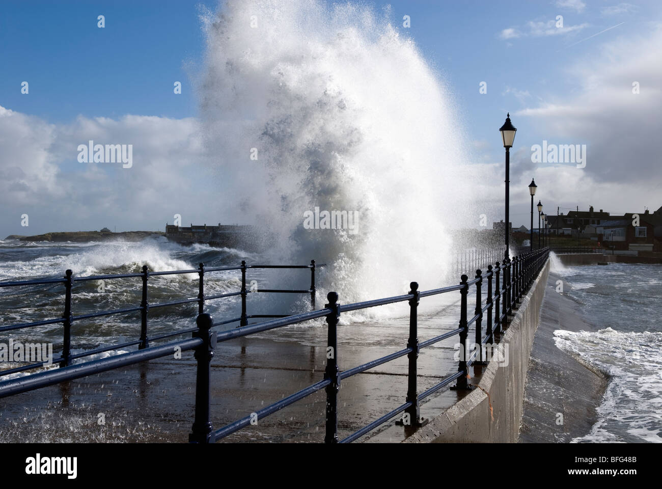 Large wave crashing over a sea wall at Amble Harbour in Northumberland ...