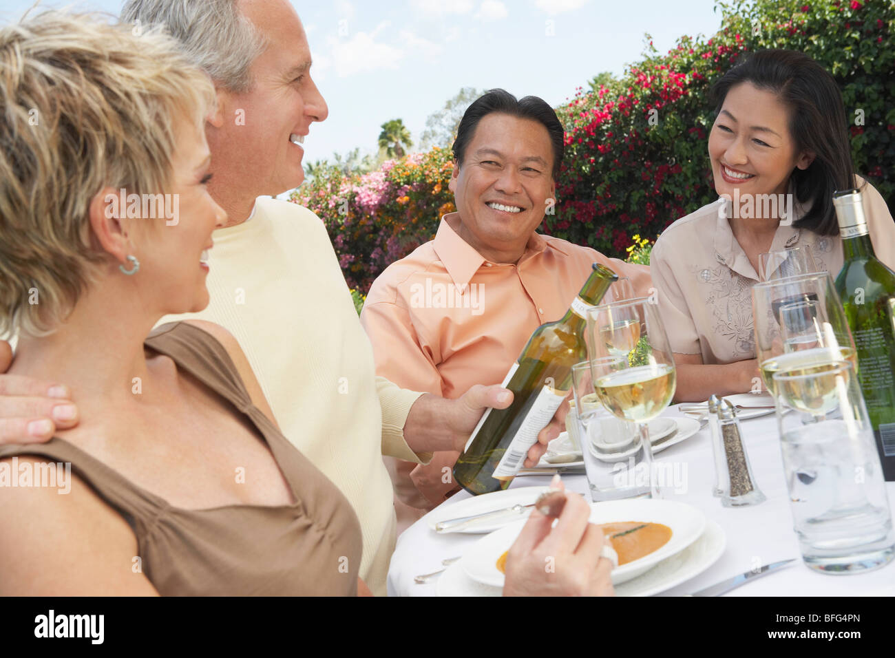 Two elegant couples dining at table outdoors Stock Photo - Alamy