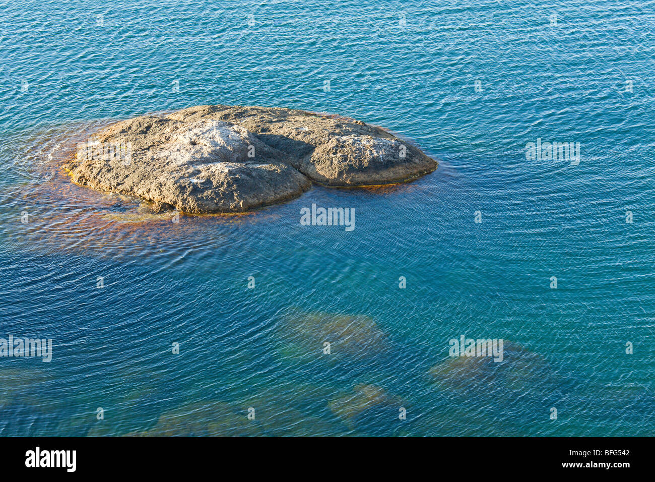 transparent coastal azure water surface with some stones on bottom ...