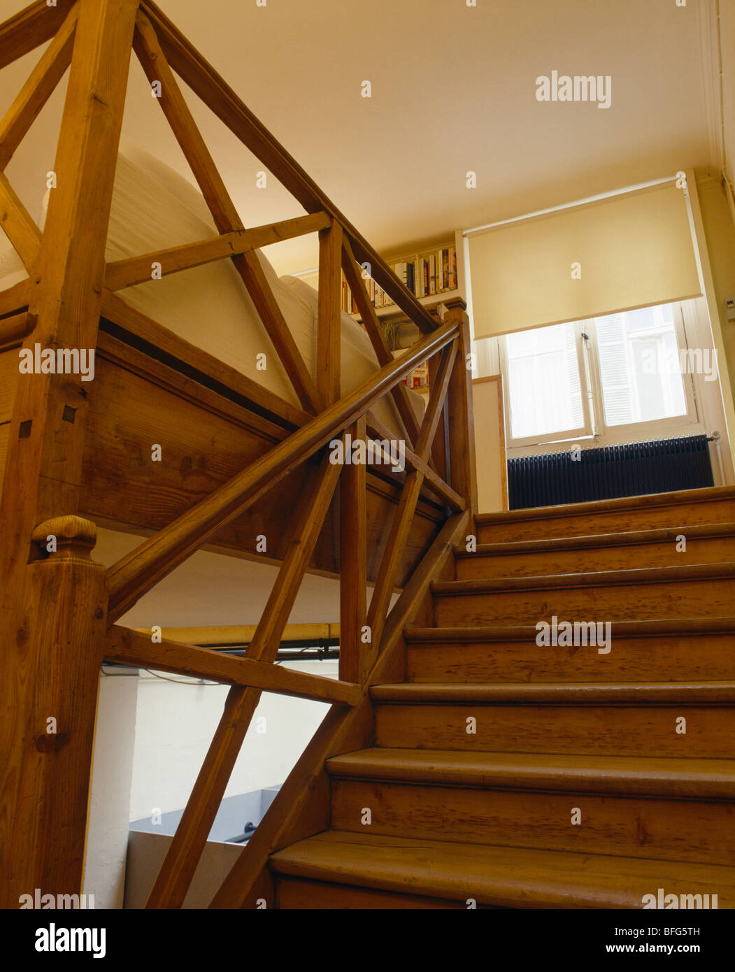 Angular banisters on wooden staircase to small cream bedroom with cream ...