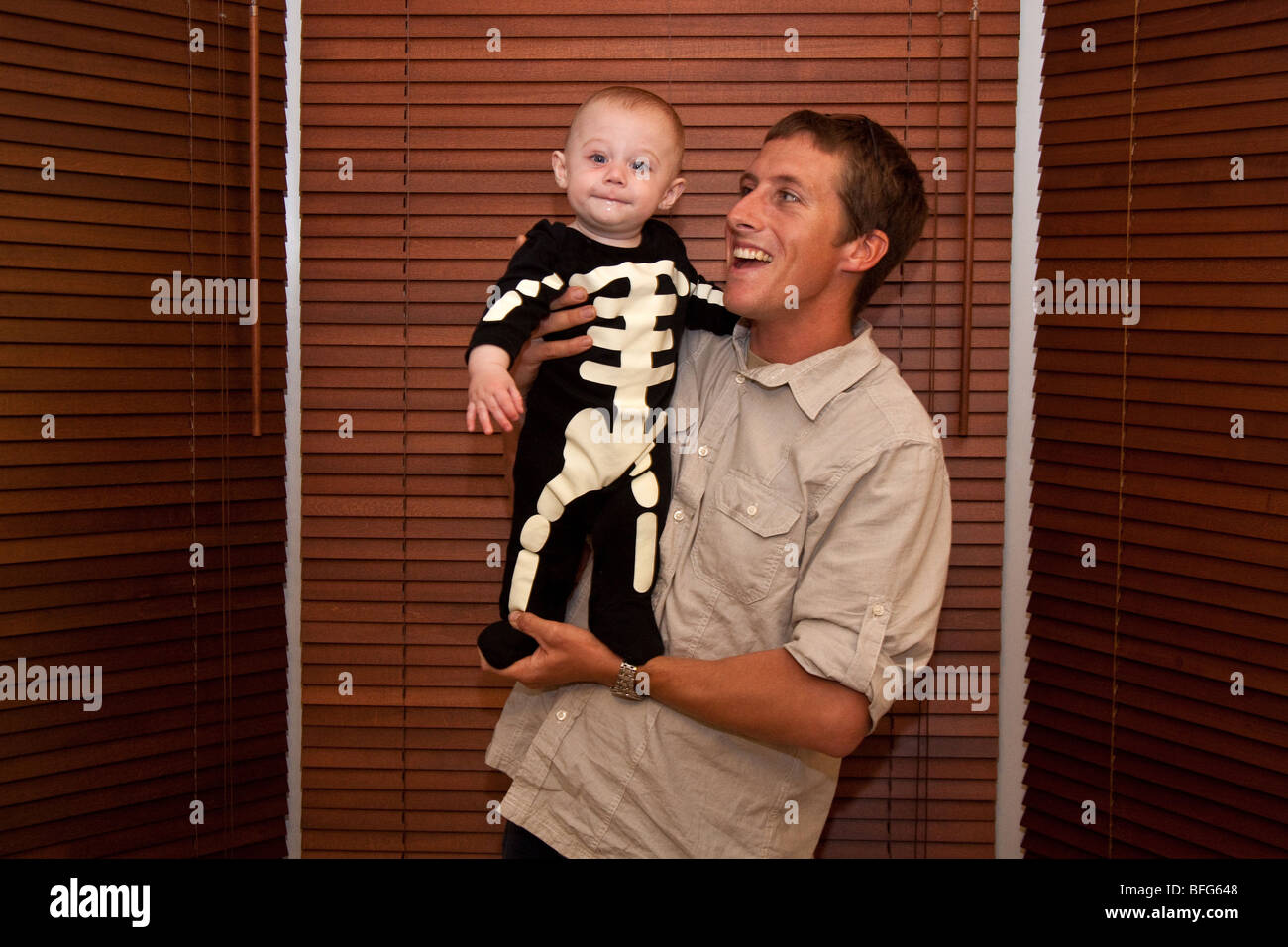 Happy baby boy (six months) in a skeleton outfit with uncle in front of ...