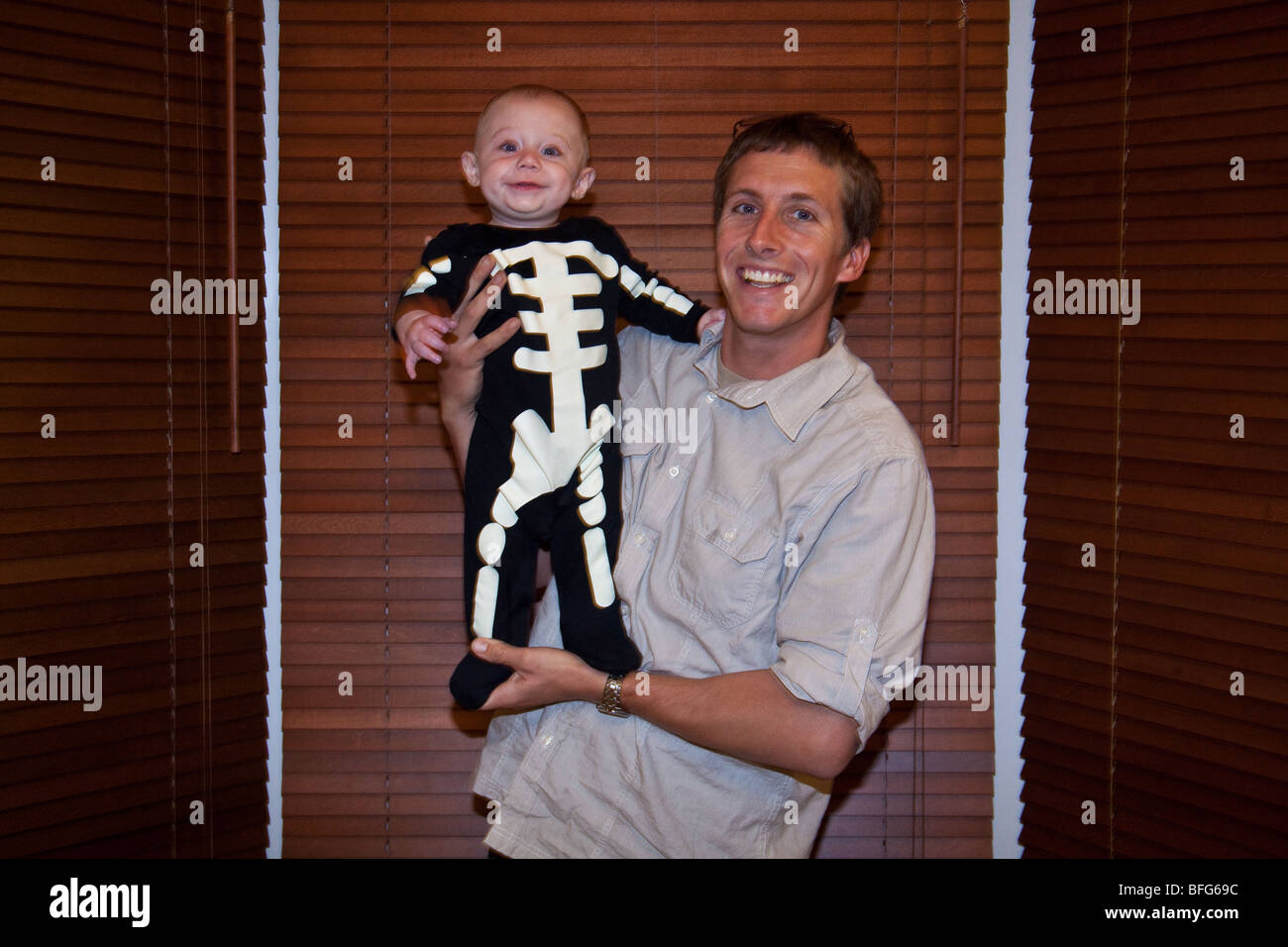 Happy baby boy (six months) in a skeleton outfit with uncle in front of ...