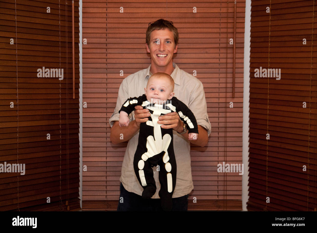 Happy baby boy (six months) in a skeleton outfit with uncle in front of ...