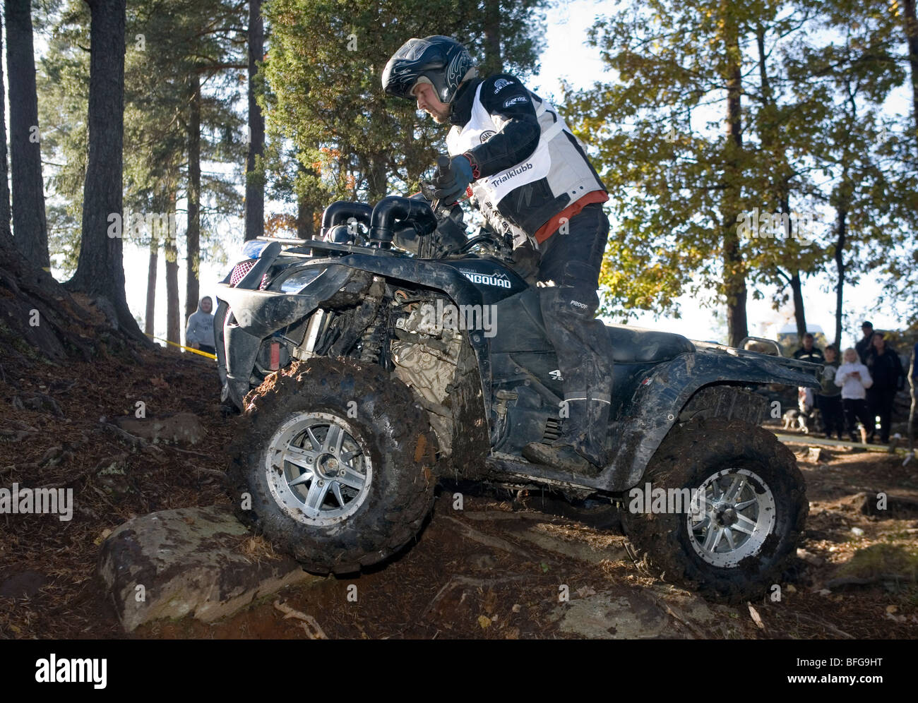 Man rides all-terrain vehicle (ATV) on rocky terrain in woods. Trial ...