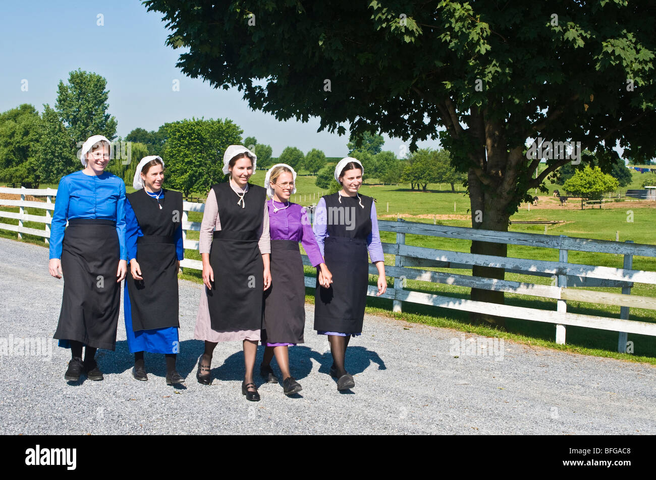 Young amish women friends walking down country lane road in Lancaster ...