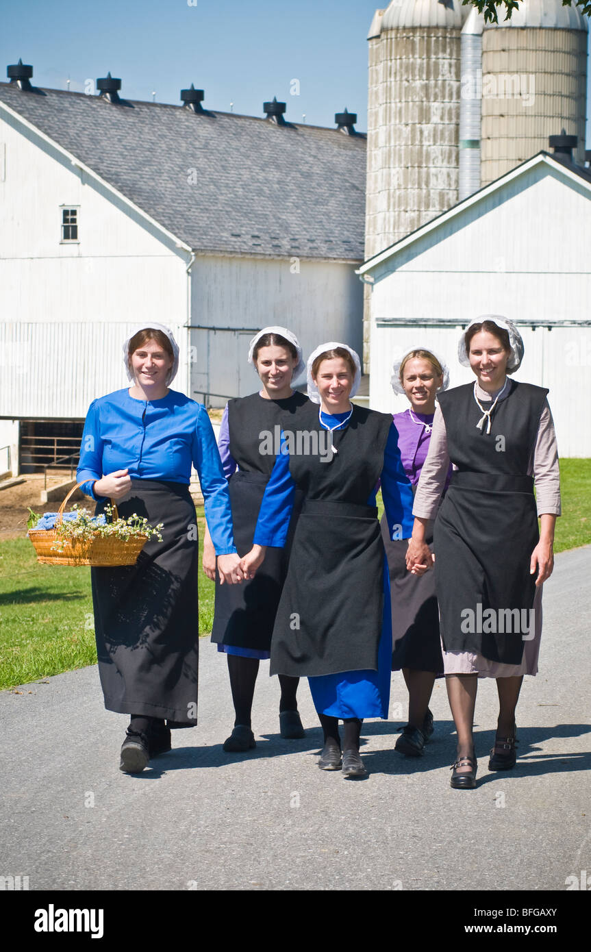 Young amish women friends walking down country lane road in Lancaster ...