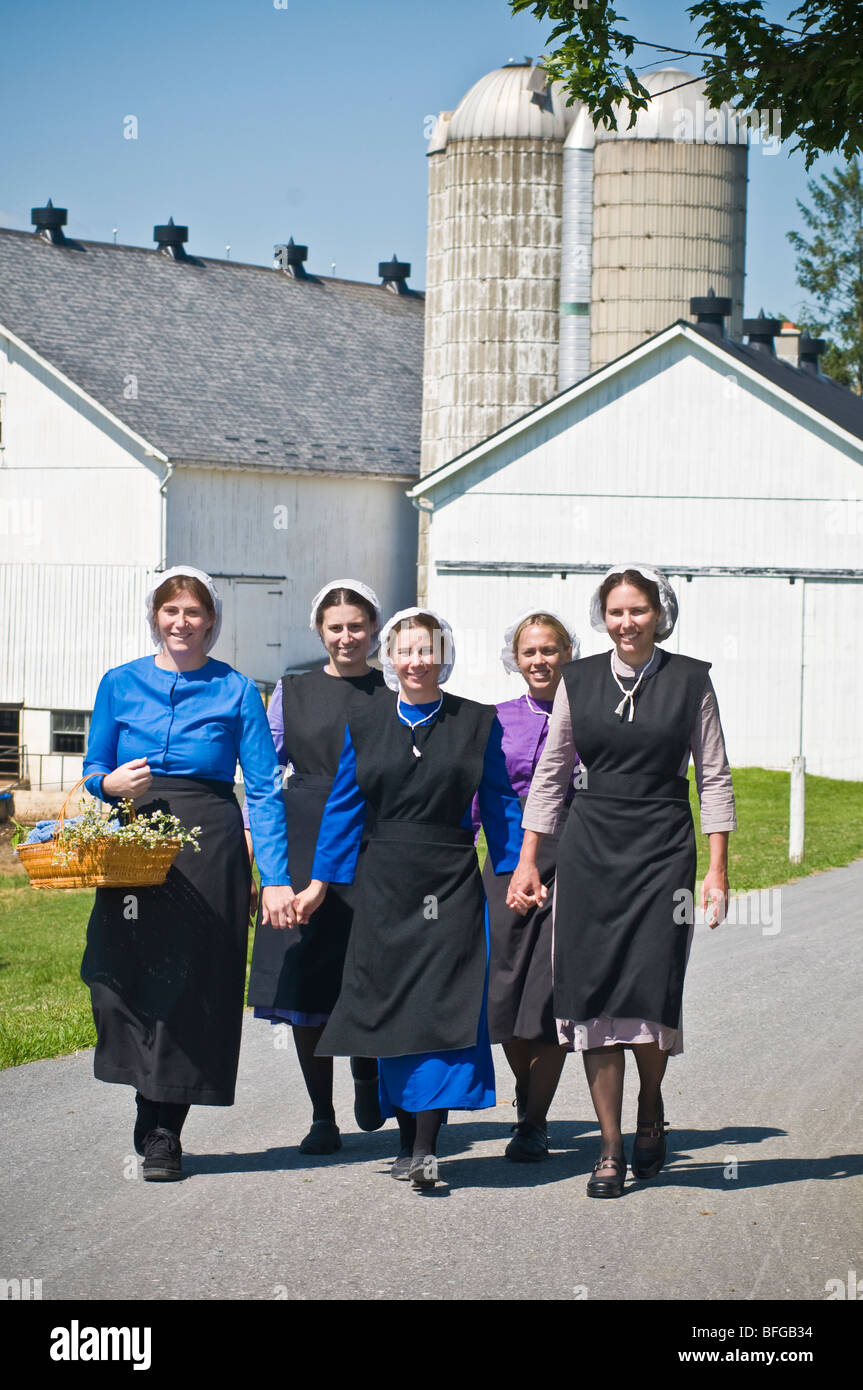 Young amish women friends walking down country lane road in Lancaster ...
